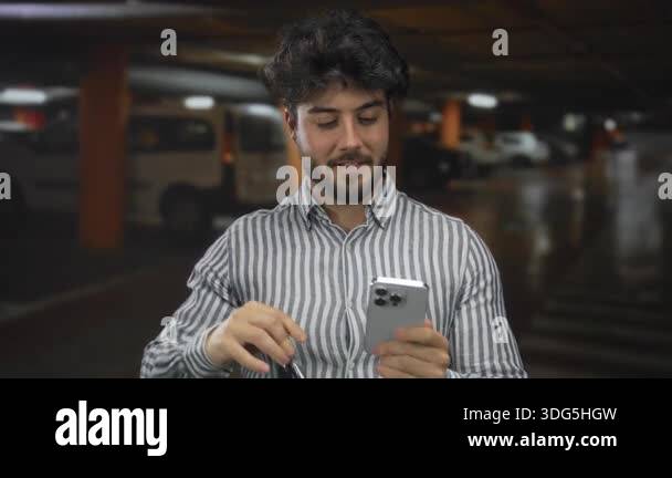 Young man with beard holding car keys and smartphone inside a dimly lit ...