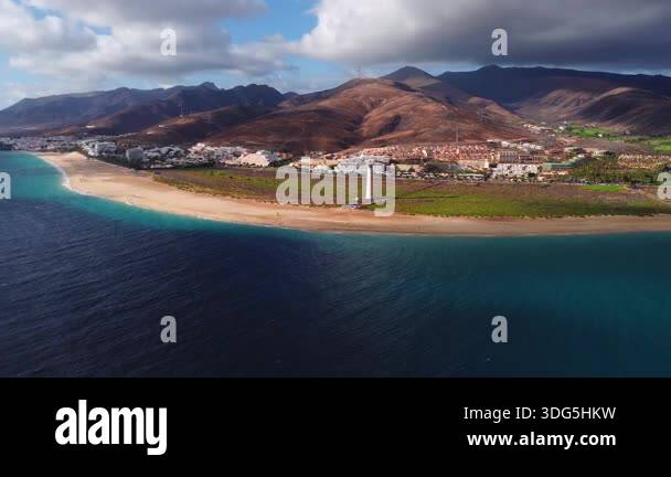 Aerial drone sweeps along Fuerteventura beach past dunes, small resorts ...