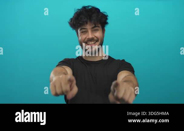 Young hispanic man with beard smiling and pointing at camera against ...