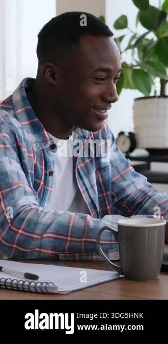 Vertical video of a smiling African American man drinking coffee while ...