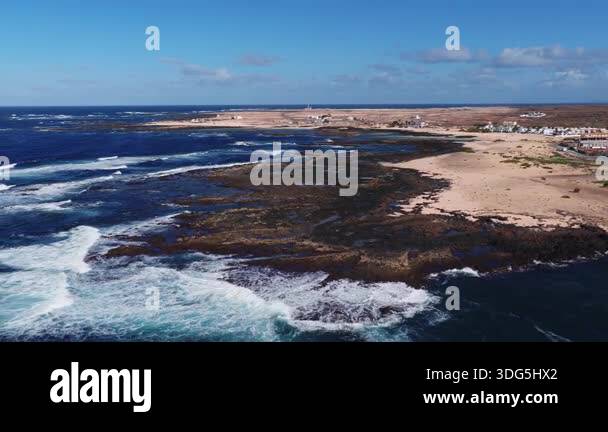 Aerial view of Fuerteventura coast, lighthouse, resort buildings, tidal ...