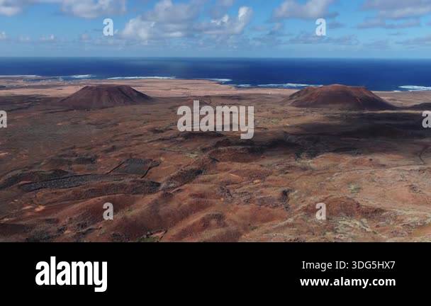 Aerial 4K view shows two cinder cones, rust red lava plain, sandy coast ...