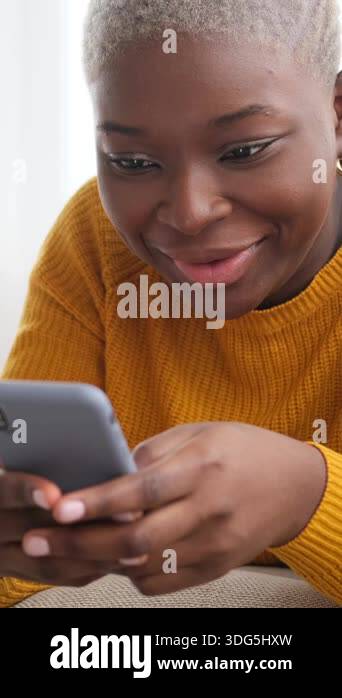 Happy African American woman using her mobile phone at home. She is ...