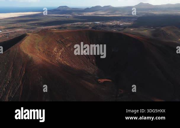 Aerial view shows a dark crater with steep walls and a small reddish ...