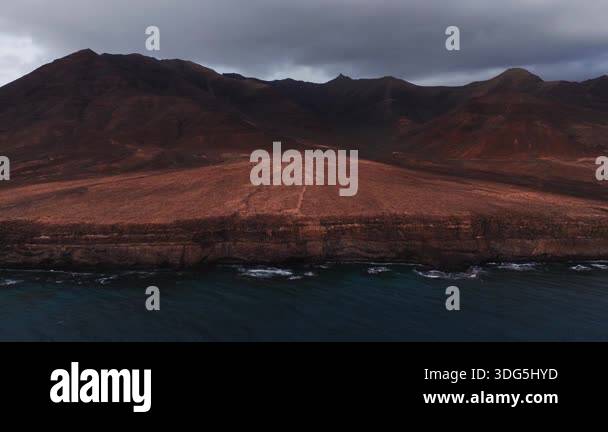 Aerial view of Fuerteventura shows rust coloured plain, steep layered ...