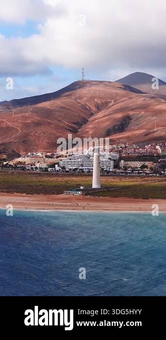 Aerial view shows Fuerteventura beach, tall white lighthouse, resort ...