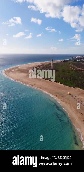 Aerial view of Morro Jable lighthouse, sandy spit, resort hotels, and ...