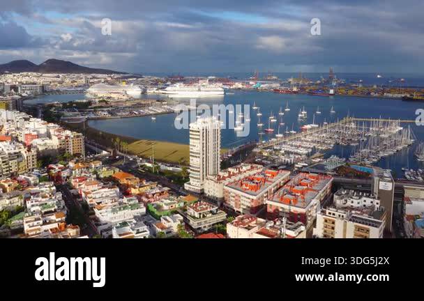 Aerial view shows crowded marina, cruise ships, container cranes, beach ...