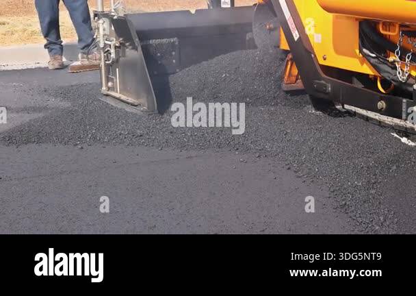 Worker uses shovel to fill pothole with asphalt in residential ...