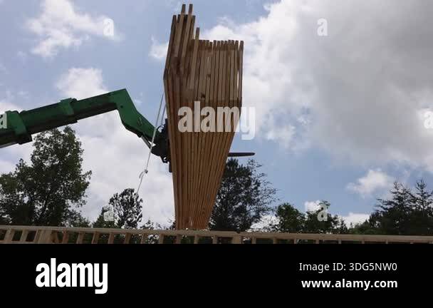 Workers are lifting long wooden trusses roofing joins beams into place ...