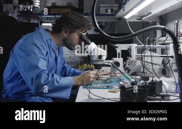 A technician man dressed in a blue lab coat is actively engaged in the ...