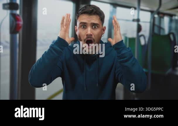 Young man on a bus with an open mouth and surprised expression, wearing ...