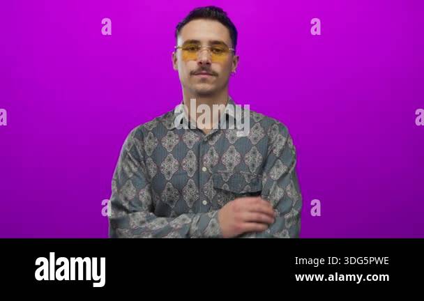 Young man confidently poses with arms crossed, wearing patterned shirt ...