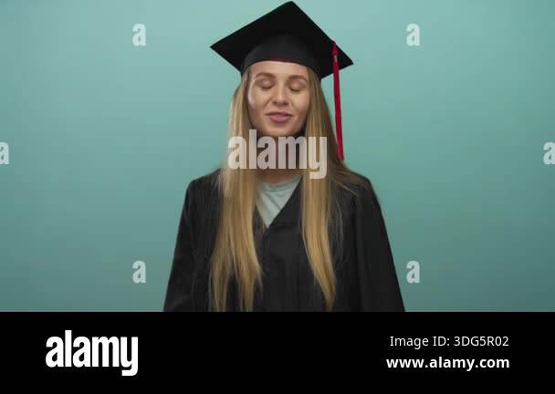 Graduated woman in cap and gown blows a kiss against an isolated green ...