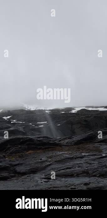 A high-altitude view captures thin waterfalls cascading down a dark ...
