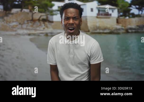 Young man frowns with furrowed brow and clenched jaw by a sunlit ...