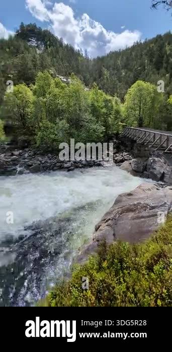 White water rushing through rocky riverbed next to wooden bridge and ...