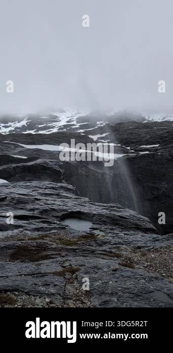 A high-altitude view captures thin waterfalls cascading down a dark ...