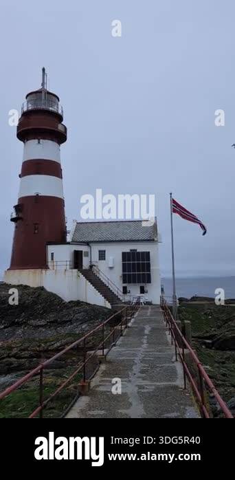 Tall red and white striped lighthouse standing next to white building ...