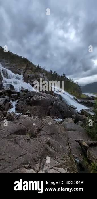 White water rushing down rocky slope next to lush green forest with ...