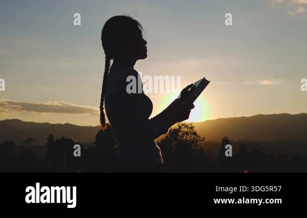 Girl prays with bible her hands sunset. read prayer dawn. human faith ...