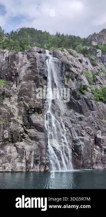 A breathtaking waterfall cascades down a steep, rocky cliffside ...
