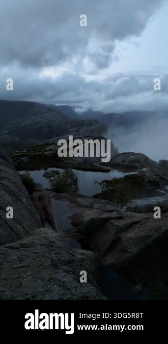 A moody, high-altitude landscape captures dark, jagged rock formations ...