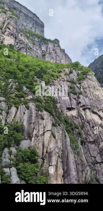 A scenic view features towering, sheer rock cliffs topped with vibrant ...