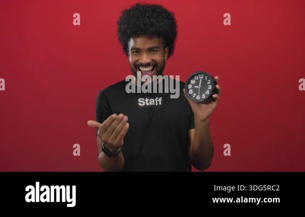 African american man in staff uniform smiles holding clock against ...