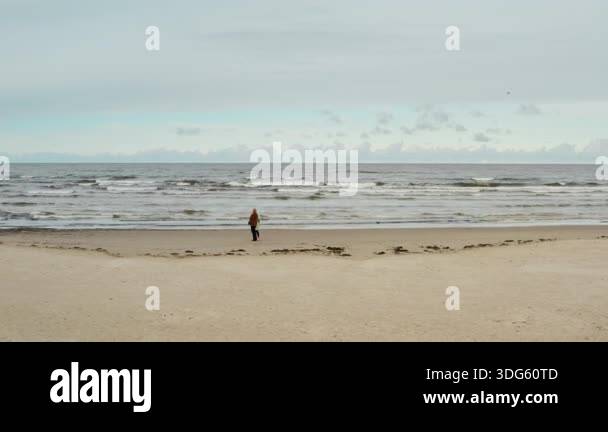 Two elderly women walking together on a wide sandy beach in Jurmala ...