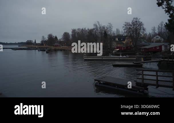 Wooden boat docks float on calm dark water in small marina at dusk ...