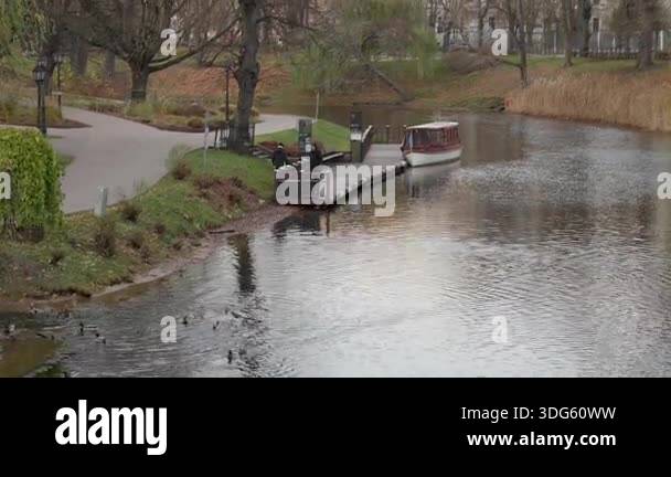 Wooden excursion boat at a dock on the city canal in a central park in ...