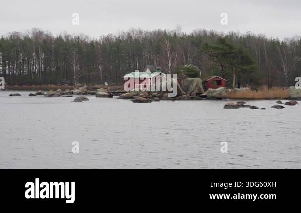 Traditional red wooden cabin stands on small rocky skerry in Gulf of ...