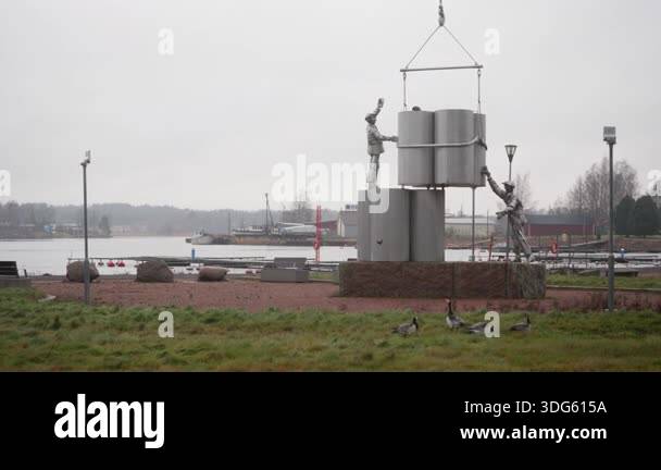Metal sculpture of harbor workers loading large paper rolls in Hamina ...