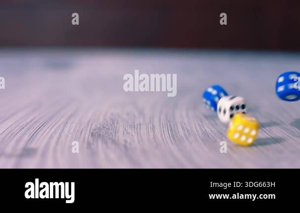 Colorful dice thrown onto table medium zoom slow motion shot selective ...