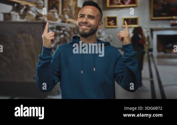 Man pointing both index fingers upward inside museum building with ...
