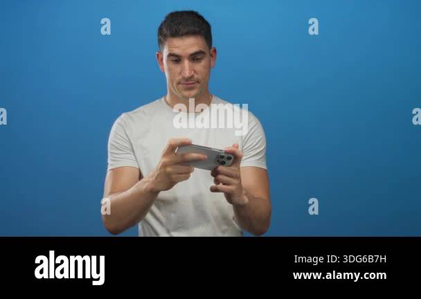 Young hispanic man holding smartphone with thumbs tapping screen ...