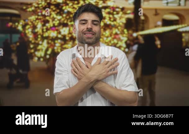 Young man crosses hands over chest on street near christmas tree lights ...