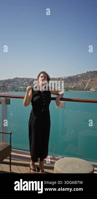 Woman leaning on ship rail smiling and holding sunglasses on building ...