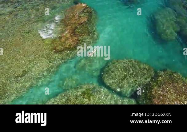 Aerial view of swimmer woman floating in clear turquoise water above ...