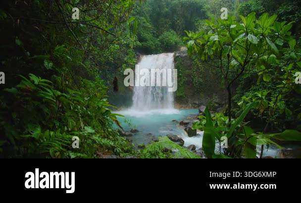 Waterfall drops into bright blue pool deep inside lush Costa Rica ...