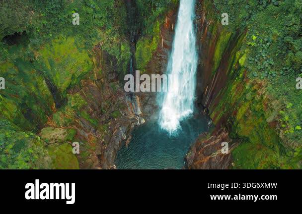 Tall narrow waterfall cascading down cliffside in Blue Falls Costa Rica ...