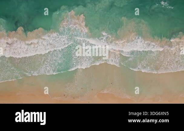 Top down drone view of sea waves crashing on golden sandy beach in ...