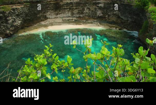 Turquoise cove with white sand beach at bottom of steep rocky cliff in ...