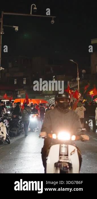 Crowd of vietnamese soccer fans waving flags on a city street at night ...