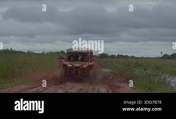 Off-road side-by-side vehicle drives fast on a muddy rural road ...
