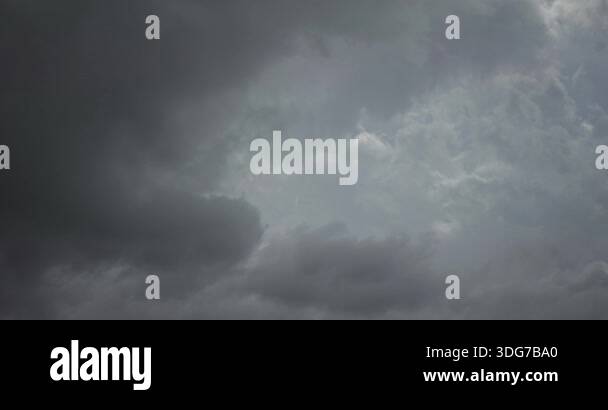Ominous dark storm clouds surrounding a brighter opening in the sky ...
