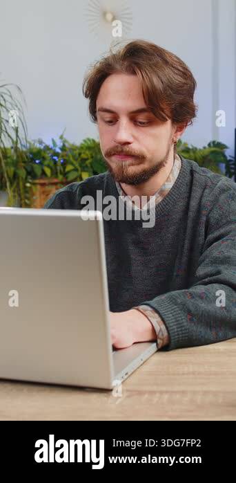 Displeased sad young man use laptop notebook typing browsing working ...