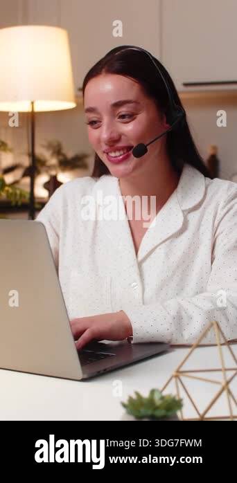 Young woman at night home works as call center agent with headset ...