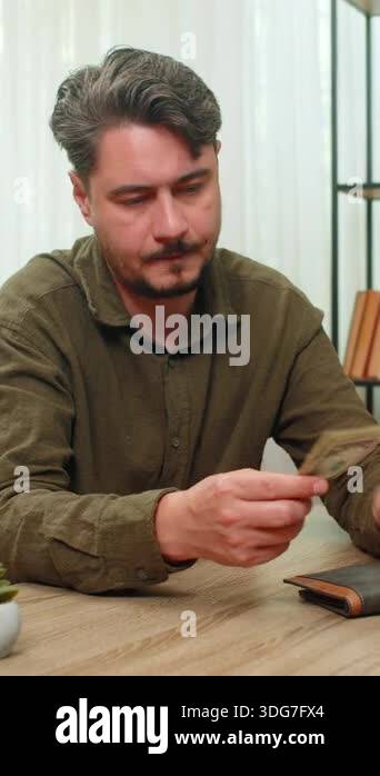 Poor sad man at home counts few cash bills frowns shaking head worried about debt poverty and ...